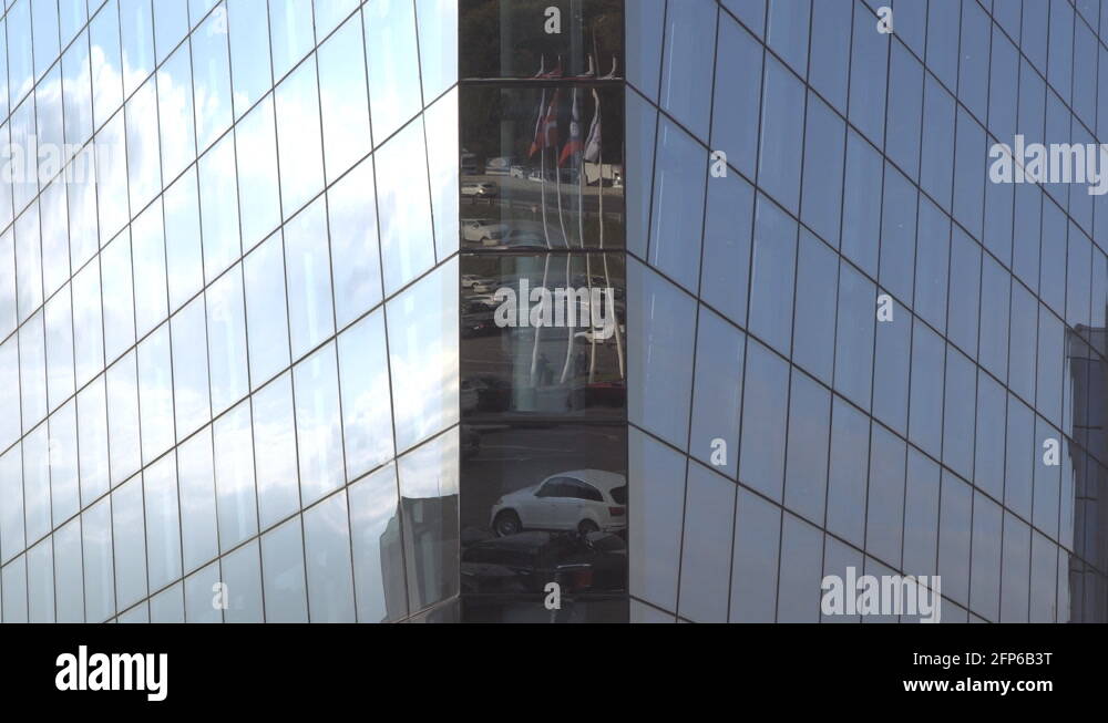 Reflection of traffic and parking lot in the glass of a modern building ...