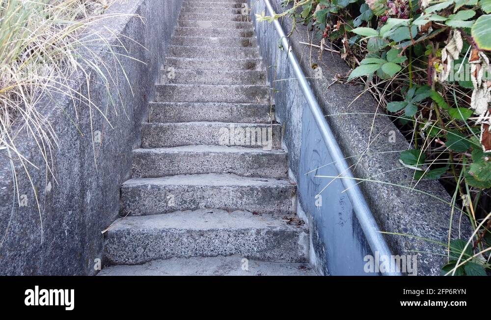 Walking up sandy concrete stairs with a steel handrail at a beach with ...