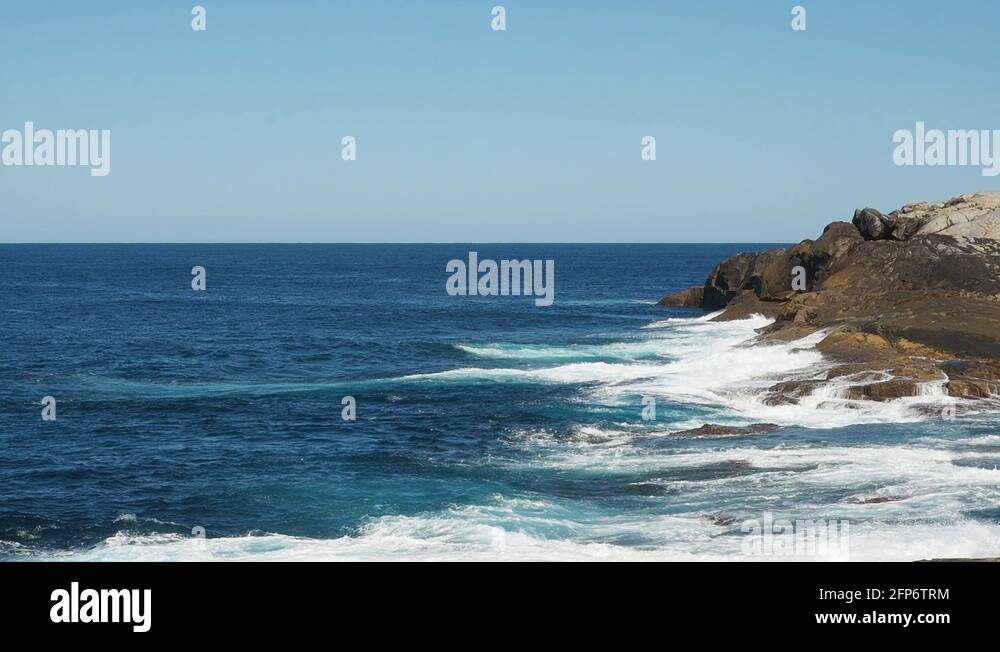 Oceanic swell on deep blue ocean breaking onto rocks. LOOPING ...