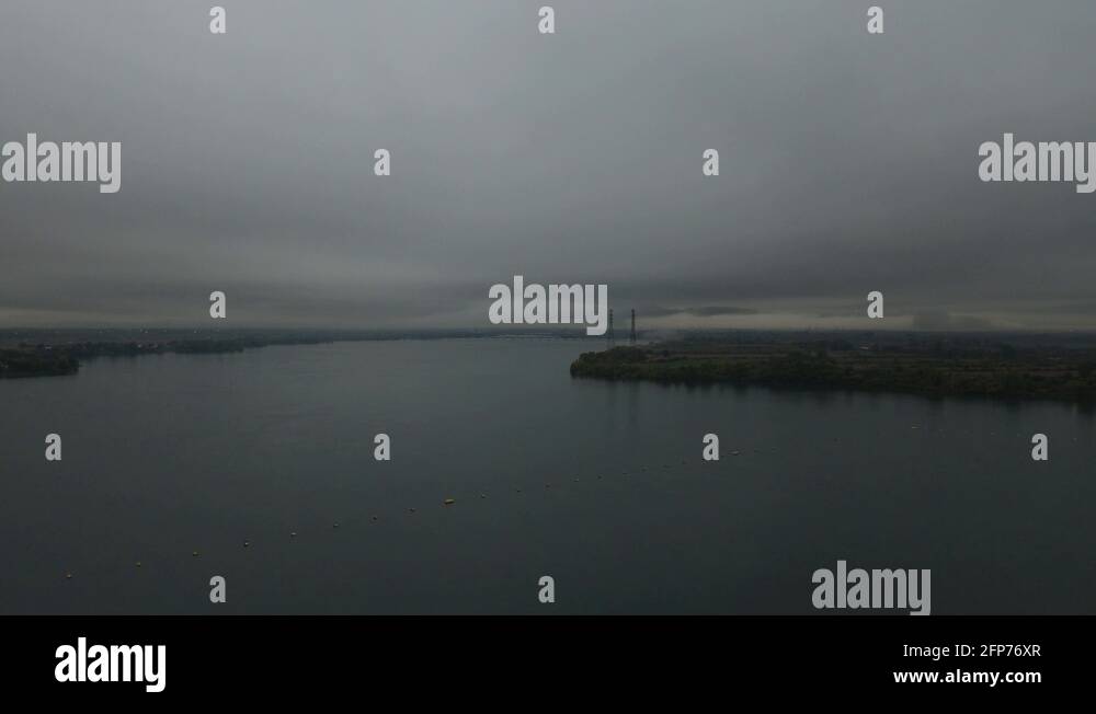 Cloudy low pressure gray clouds lay over large body of water on bird's ...