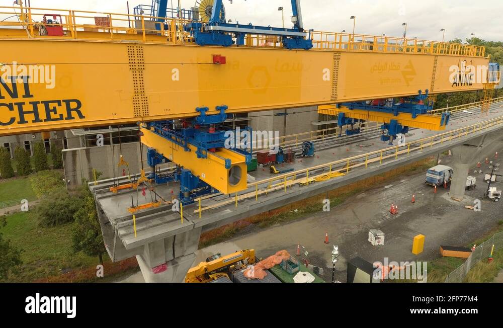 Drone rising vertically exposing large horizontal crane with trees and ...