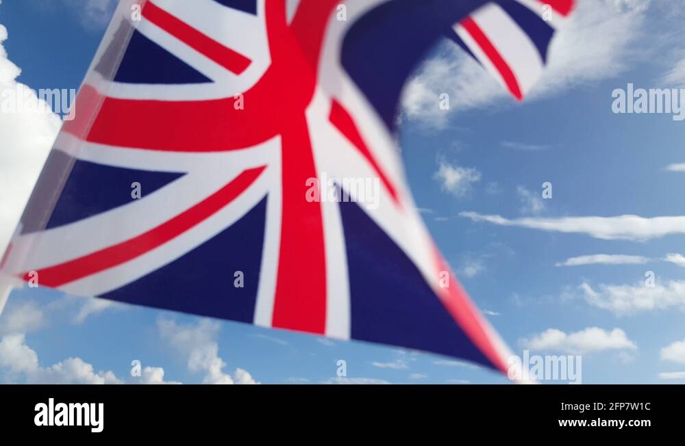 British flag waving on bright sky with clouds background, heavy wind ...