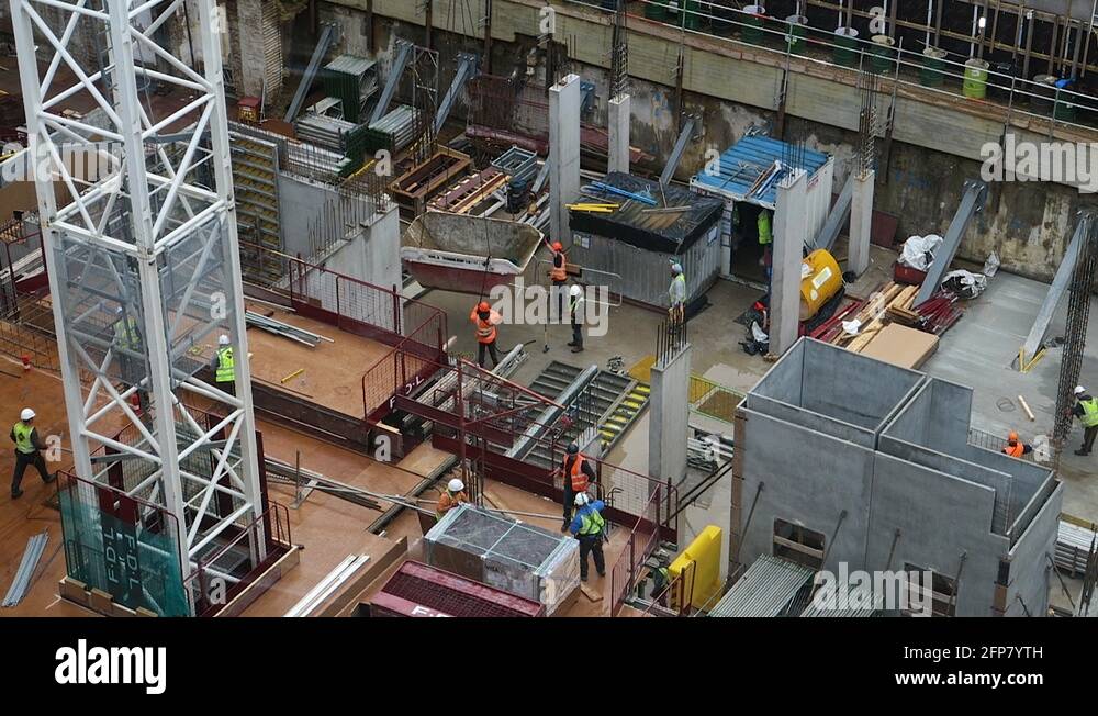 Construction Workers Assisting Crane Operator With Placing Skip On ...