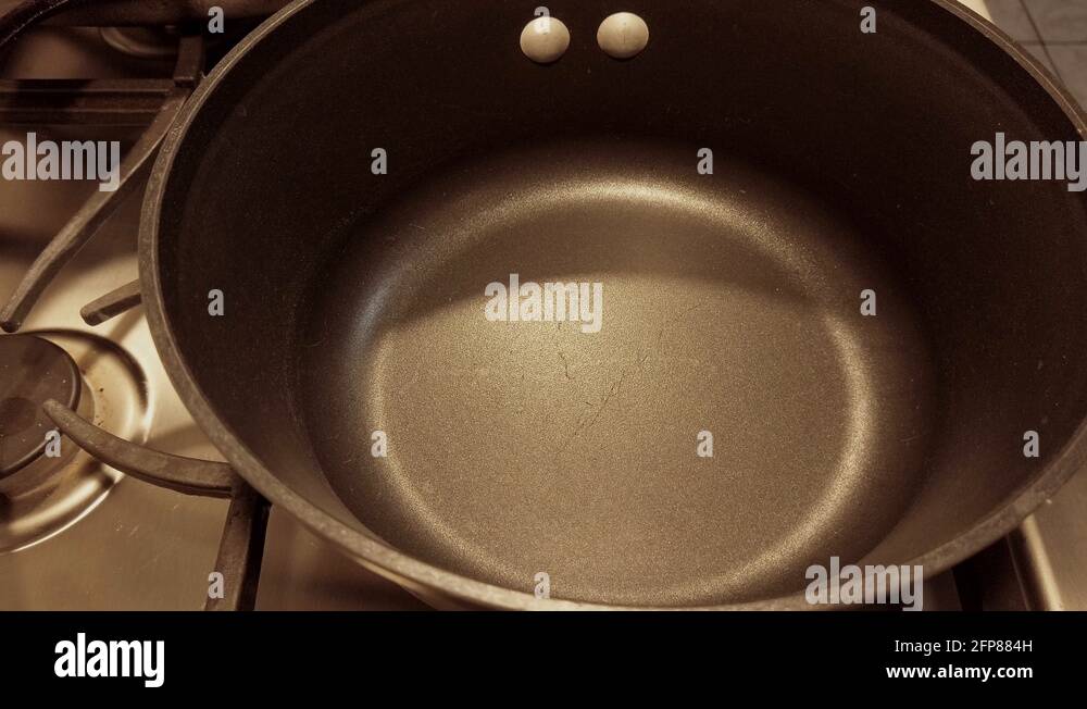 No person, non-stick pan on fire pouring olive oil, side profile shot ...