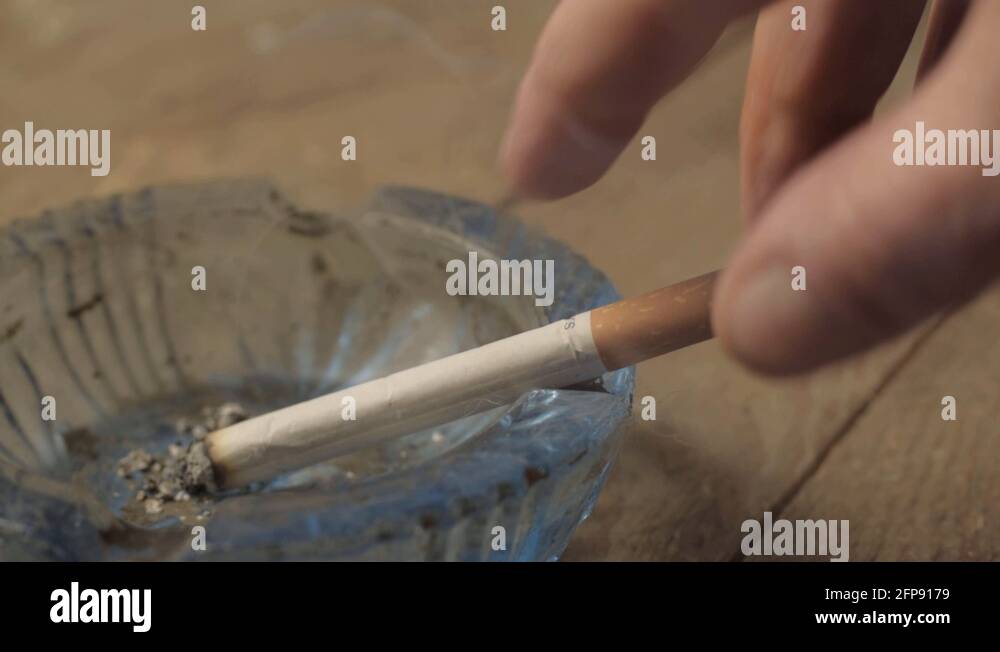 Smoker flicking ash off a burning cigarette into an ashtray Stock Video ...