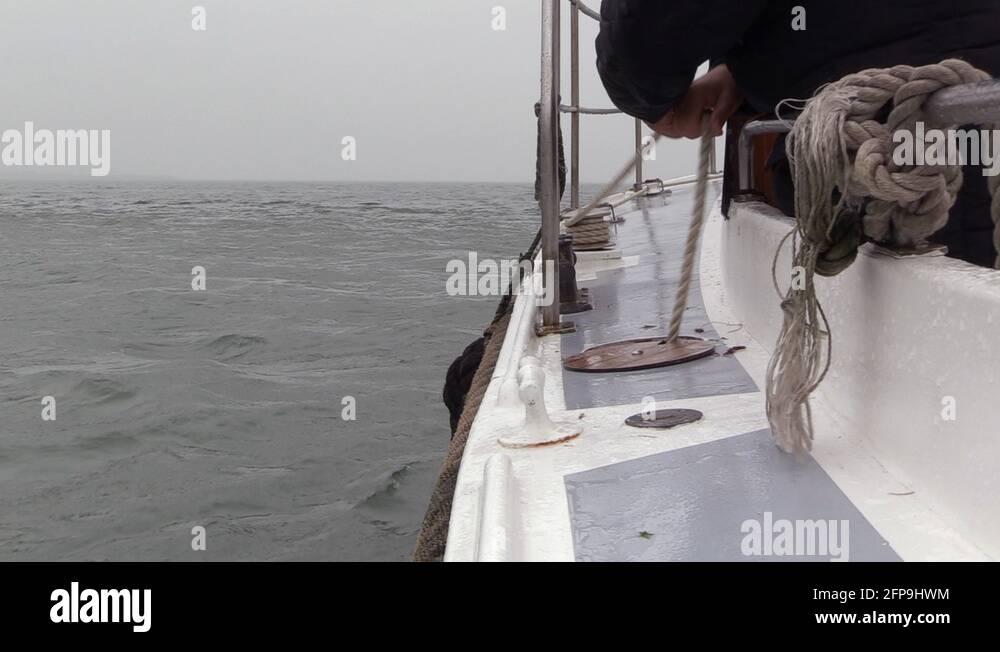 Man pulls an anchor rope on the side of a small boat, rear view Stock ...