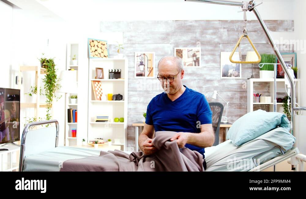 Nurse helping a disabled retired old man to stand up from his hospital ...