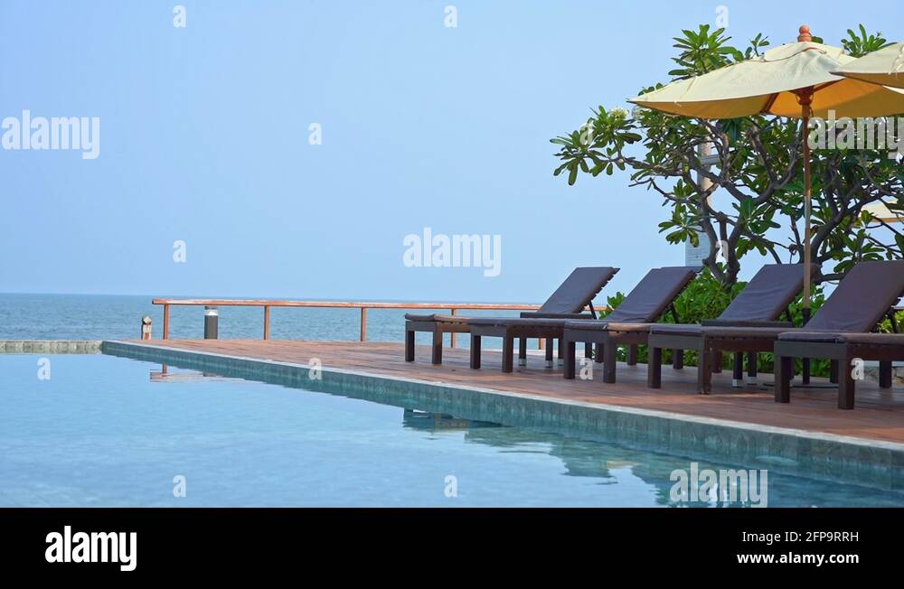 Lounge Seats by swimming pool at luxury resort next to ocean background ...