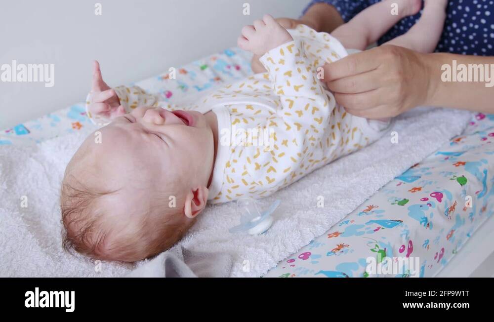 Mother settles crying baby girl with pacifier as she unbuttons her ...