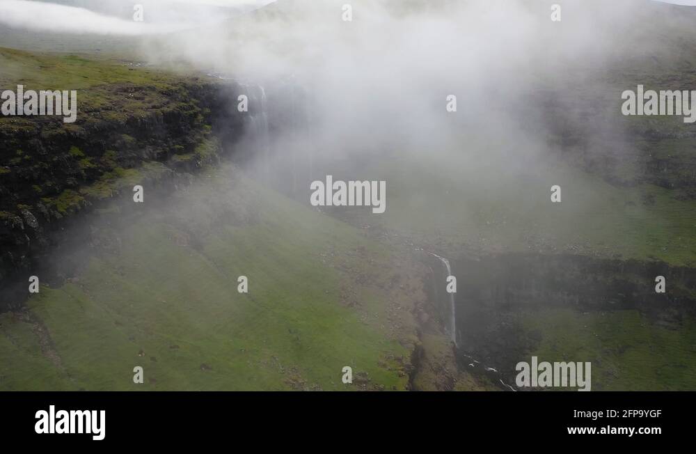 Fossá Waterfall, coastal falls in Faroe Islands through misty clouds ...