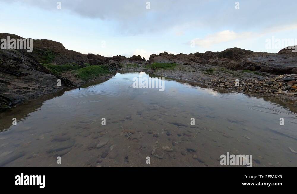 Rainwater rippling in shallow water at pebble beach in South Ireland ...