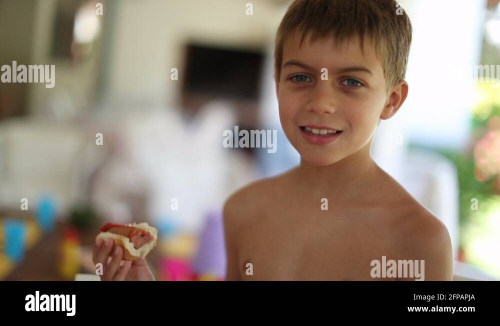 Young boy eating hot-dog. handsome child eats fast-food snack portrait ...