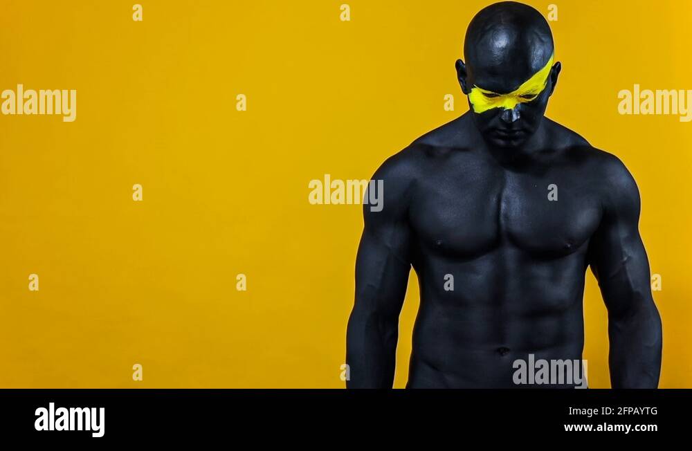 Man bodybuilder athlete with yellow color on face art and black body ...
