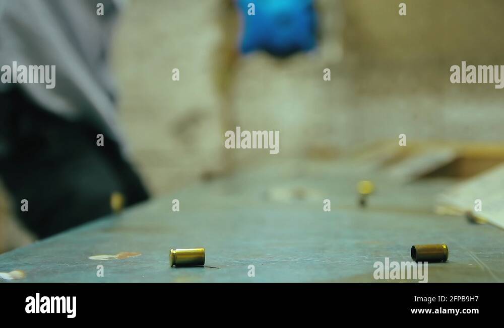 Cinemagraph of empty pistol bullet shell dropping and impacting wooden ...
