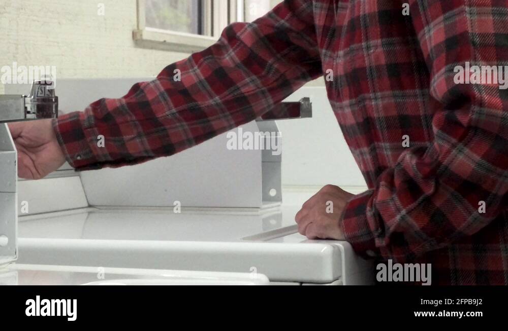 Caucasian woman adjusts settings on commercial dryer and puts coins in ...