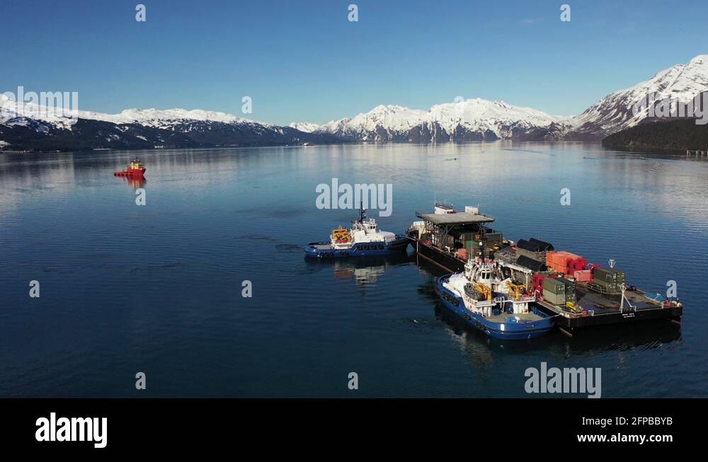 Barge full of shipping container cargo being guided by tug boats in ...