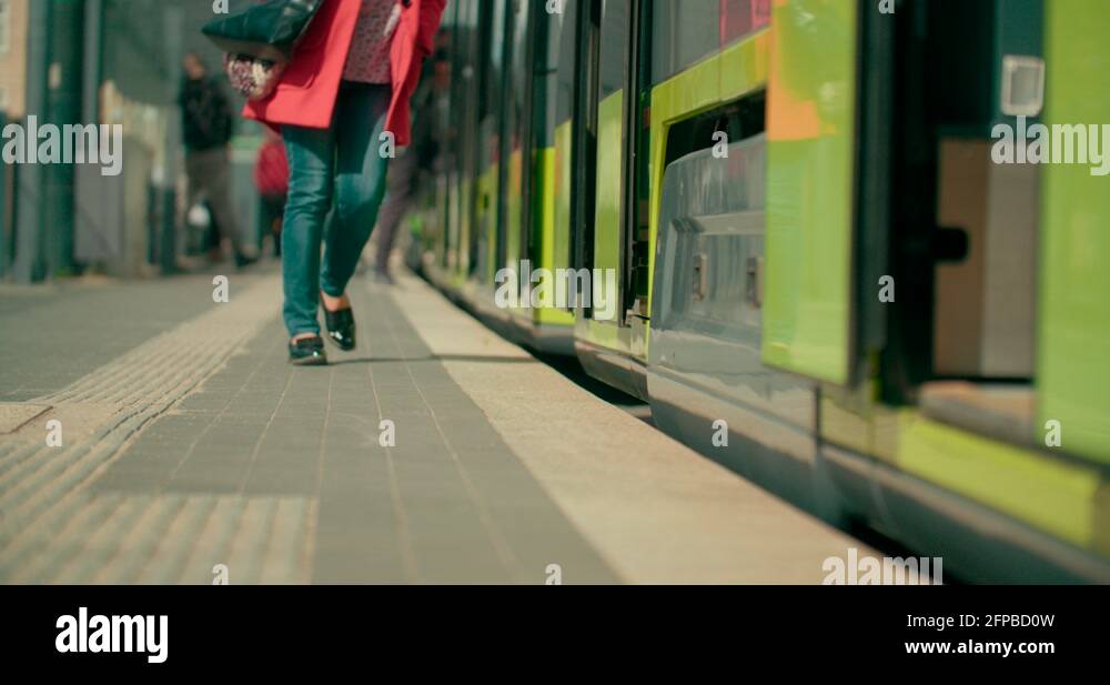 Commuter feet walking onto tram train doors on station metro platform ...