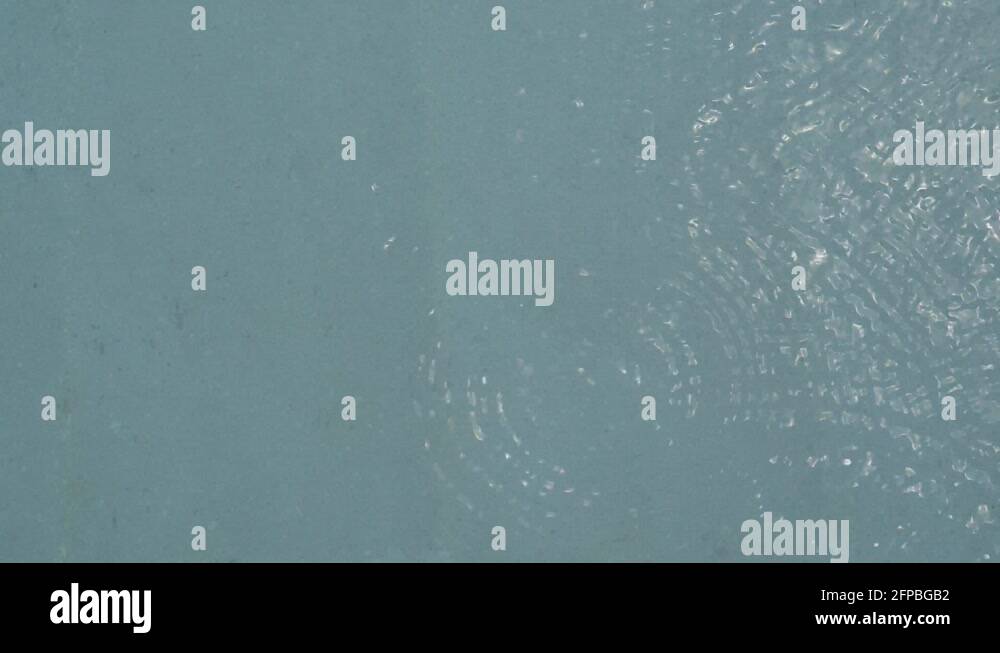 Rain splashing into swimming pool. Close up of swimming pool during ...