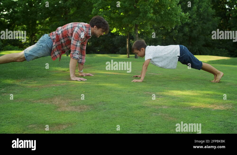 Boy and man standing in plank position. Father and son doing push ups ...