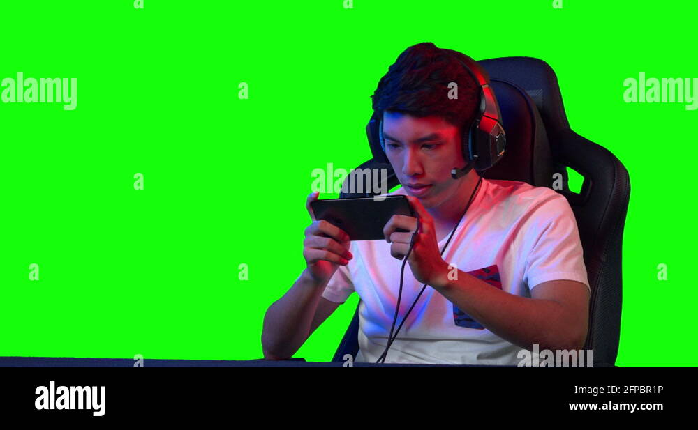 Pro cybersport gamer play online mobile game over green screen ...
