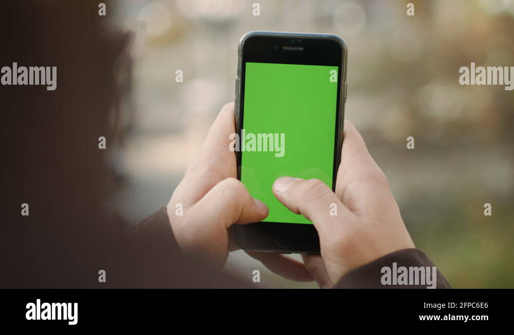 Guy hands touching cellphone green screen. Man texting by mock up phone ...