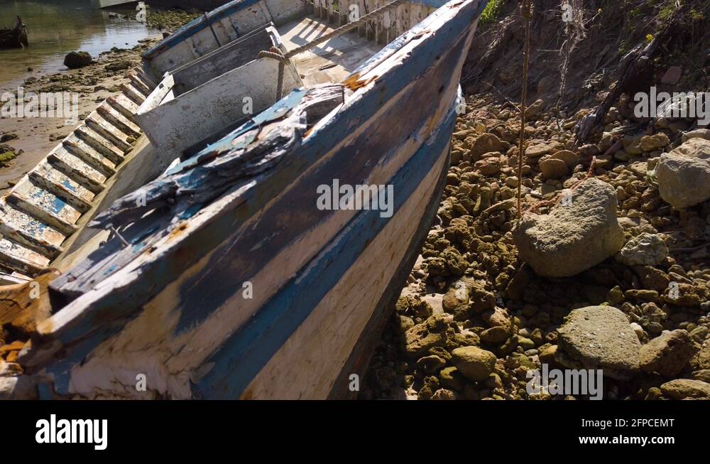 Shipwrecked Boat with Blue and White Stripes on Rocky Beach, Closeup ...