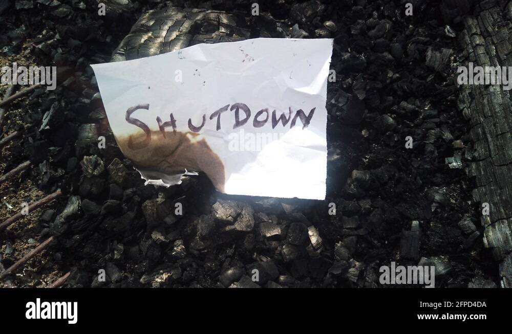 White piece of paper sign lit on fire in firepit with black block ...