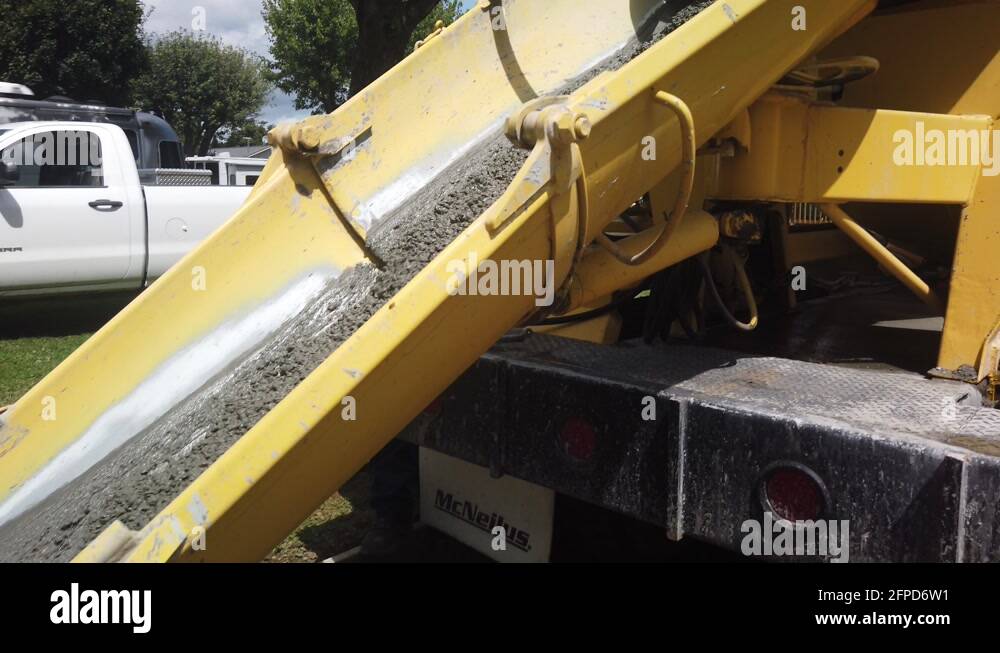 Cement trough from cement truck pours down the trough onto the dirt ...