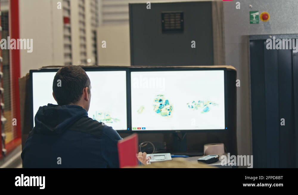 Customs worker using modern x-ray scanning equipment to inspect ...