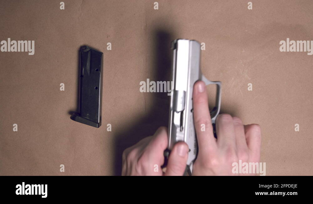 Top Down shot of hands field stripping a 9mm pistol in real time ...