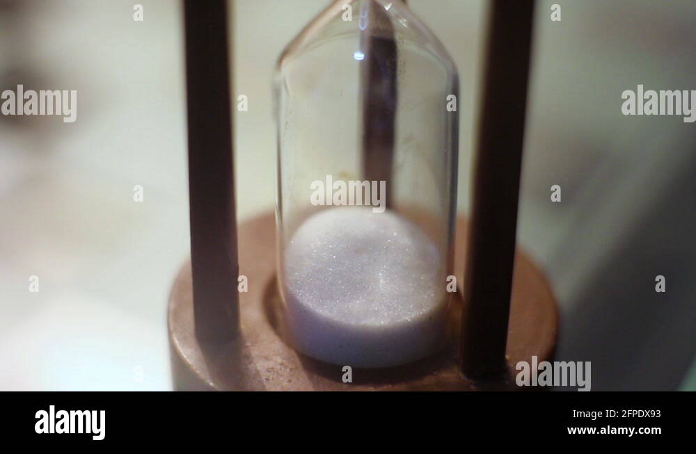 Macro footage of sand falling to the bottom of vintage wooden hourglass ...