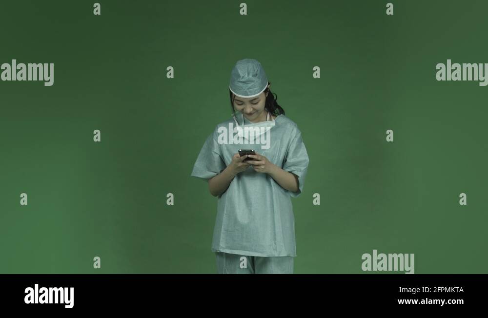 young asian surgeon isolated on green-screen background with cell phone ...