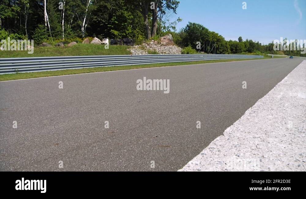 A blue race car streaks past the camera on a straightaway at Calabogie ...