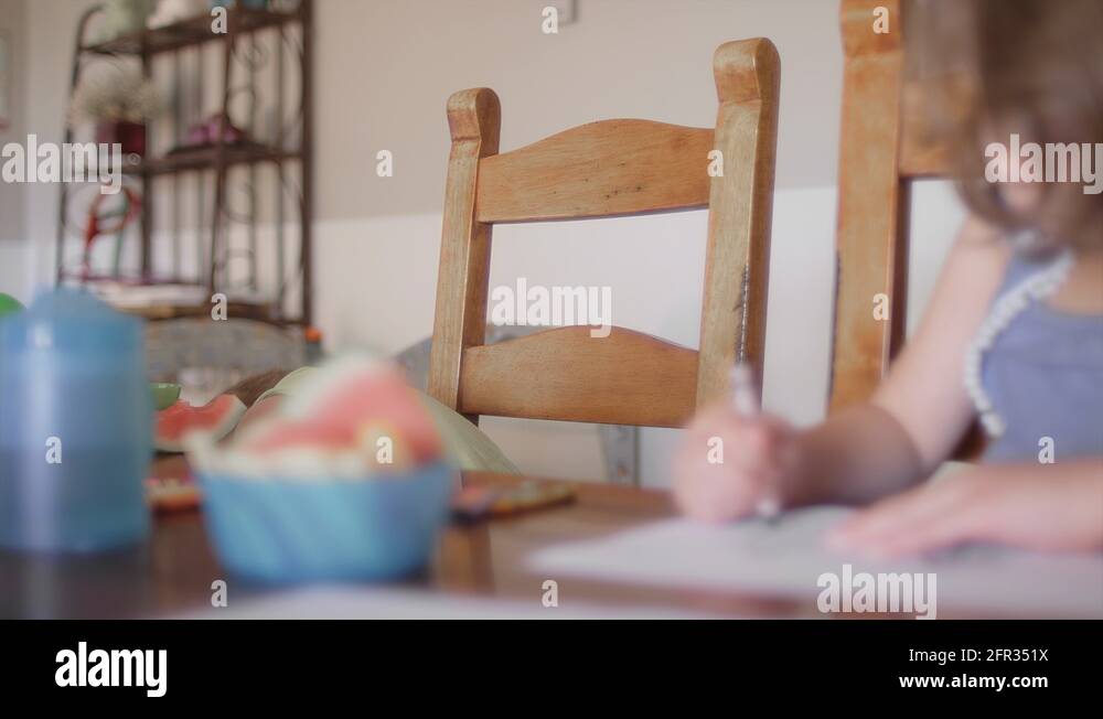 A silly little girl sliding out of her chair after coloring at at a ...