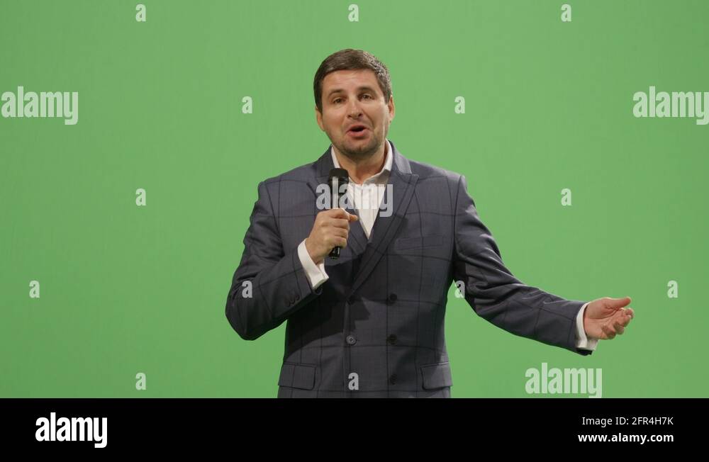 Media reporter with a microphone is talking on a mock-up green screen ...