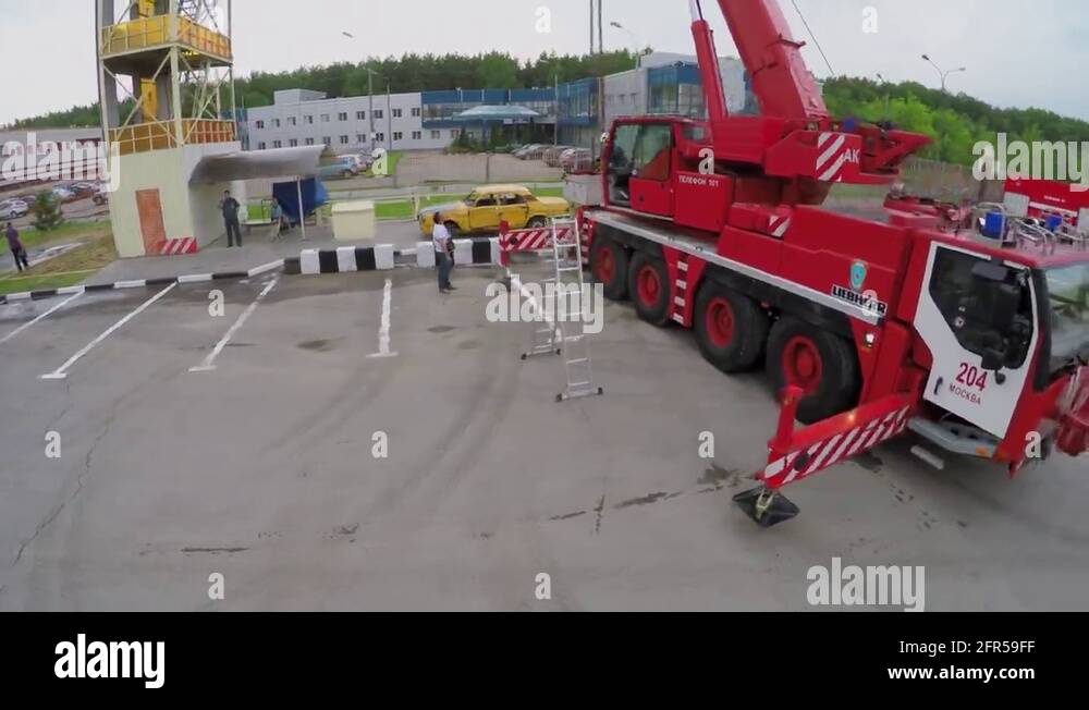 Fireman work on fire-crane near tower on territory of fire station ...