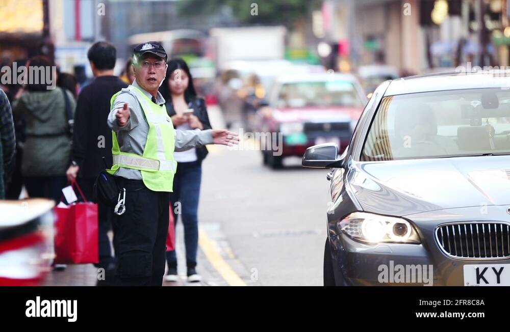 Traffic warden directing cars on a busy road in Hong Kong Stock Video ...