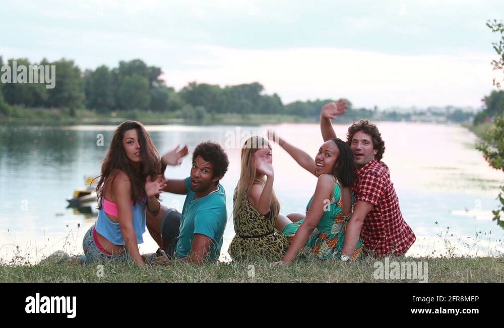 Back view of group of friends, turning around and waving to camera ...
