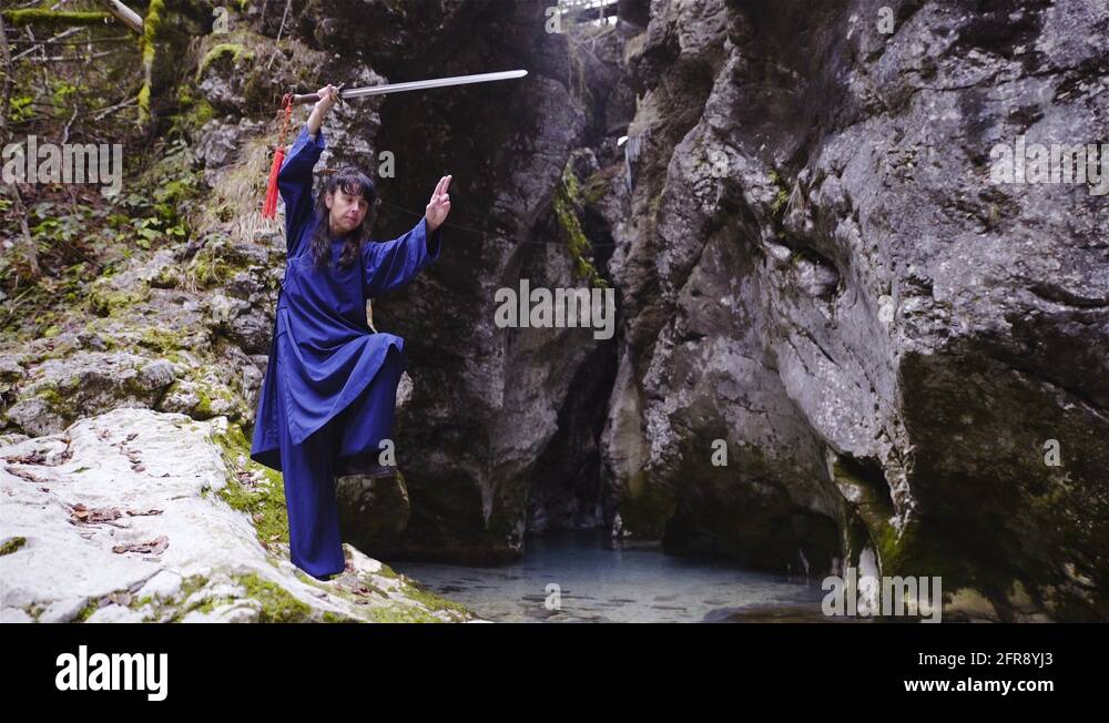 Kung Fu pose with katana sword over head beside rock canyon 4K Stock ...