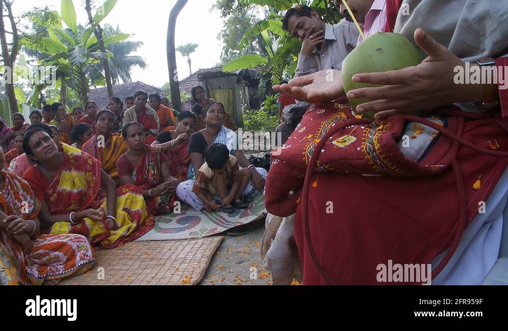 Tight shot of a man addressing a small crowd of Indian women sitting on ...