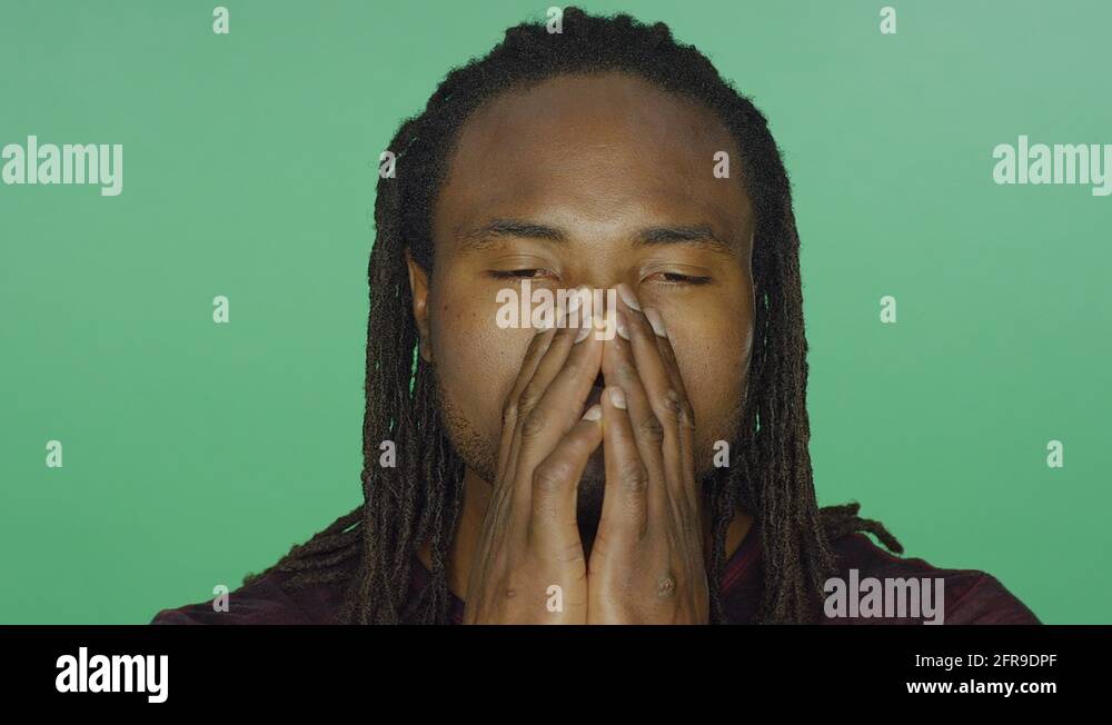 A black man with dreads looking sad and covering his face with his ...