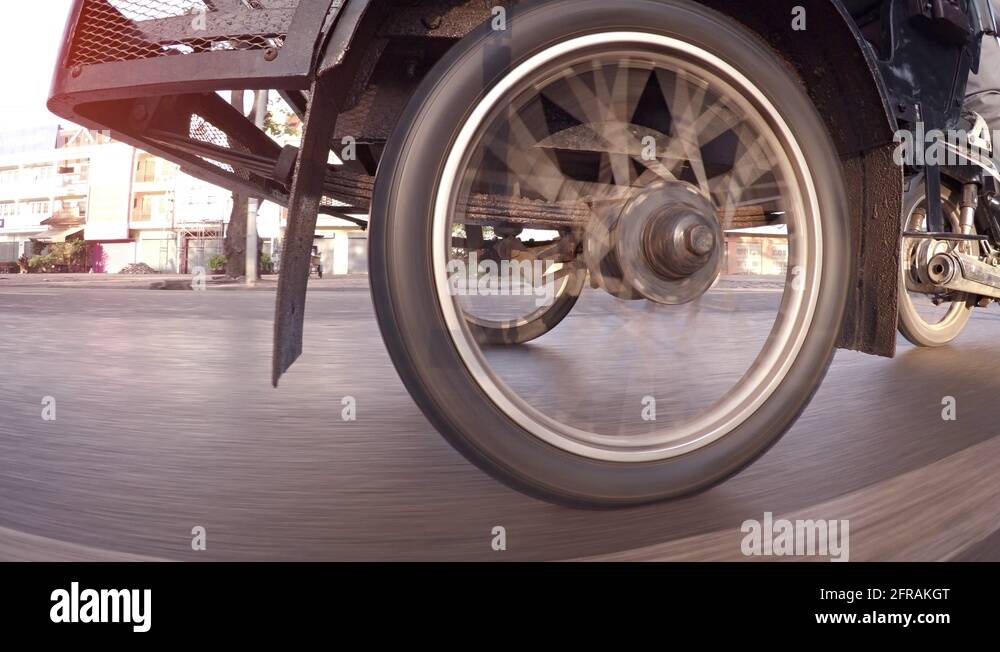 Wheel of a motor rickshaw spinning as it cruises down a city street ...
