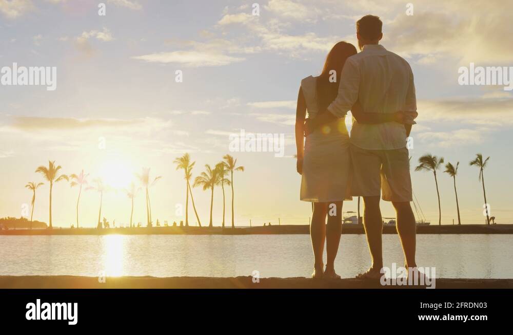 Romantic couple at sunset embracing enjoying watching the sun set over ...