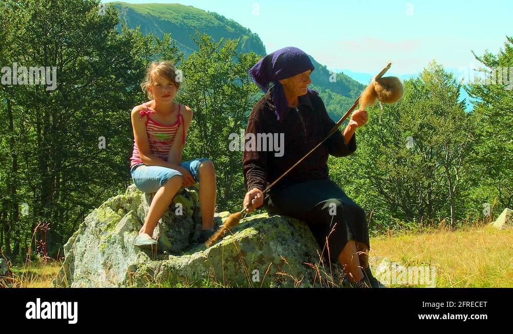 Old woman spinning wool and used distaff and spindle to make a yarn ...