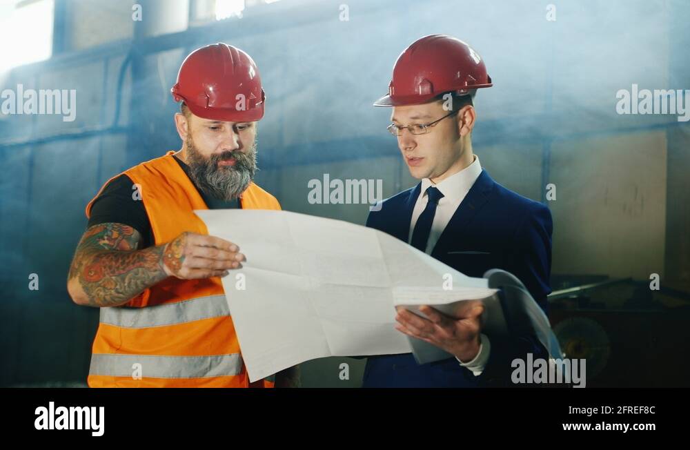 Architect and builder in a helmet with a beard together studying ...