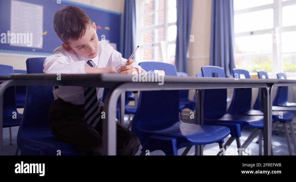 4K Little boy sitting alone to do his work in school classroom Stock ...
