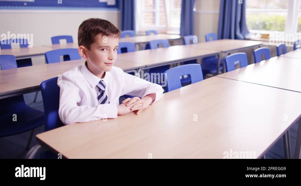 4K Portrait of happy little boy sitting alone & laughing in school ...