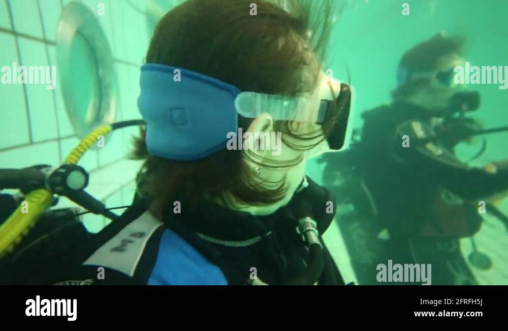 Woman in wetsuits with scuba in swimming pool and girl out of focus ...