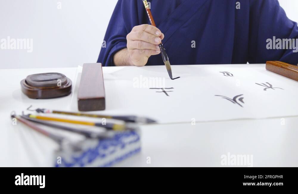 Dolly slide over table with person drawing calligraphy characters 4K ...