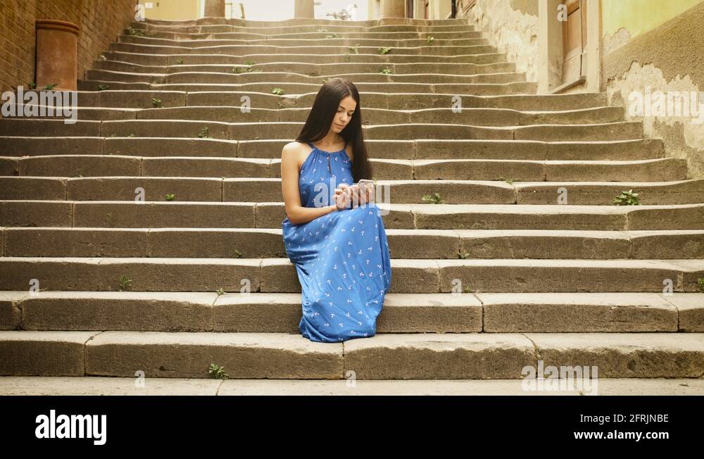 Attractive Young Brunette Woman in Light Summer Dress Sitting on Steps ...